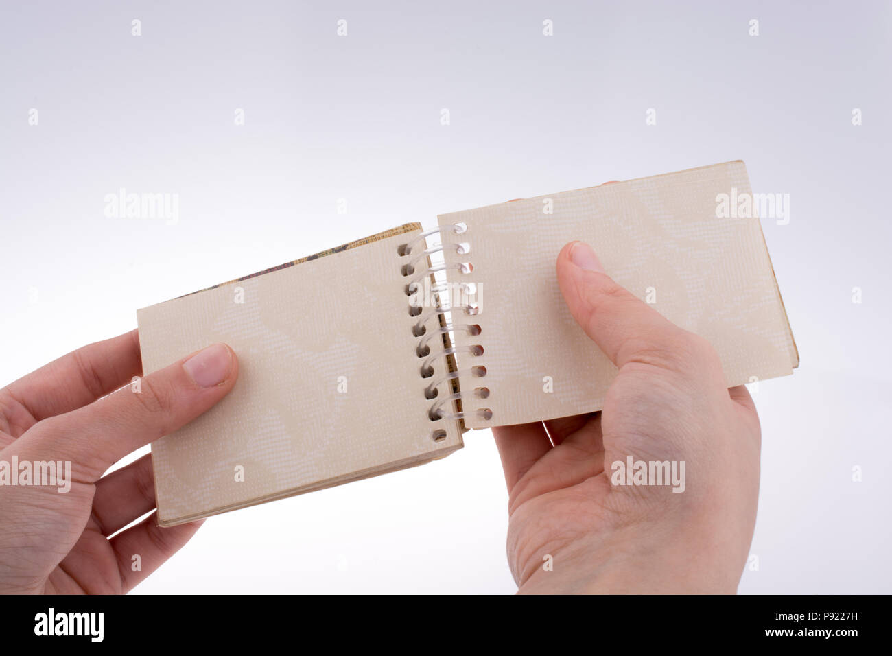 Hand holding a spiral notebook on a white background Stock Photo - Alamy