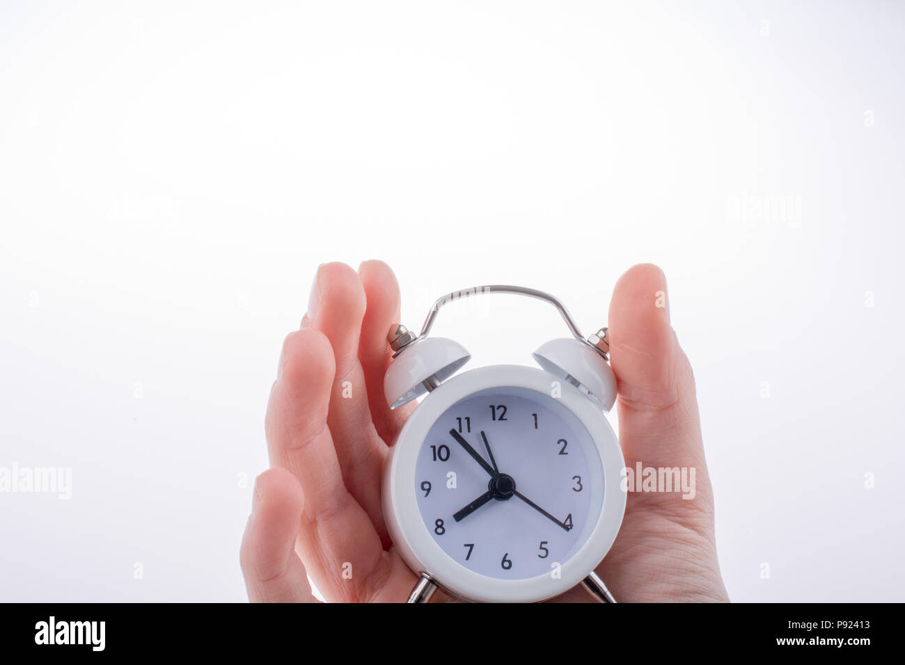 Alarm clock in hand on a white background Stock Photo - Alamy