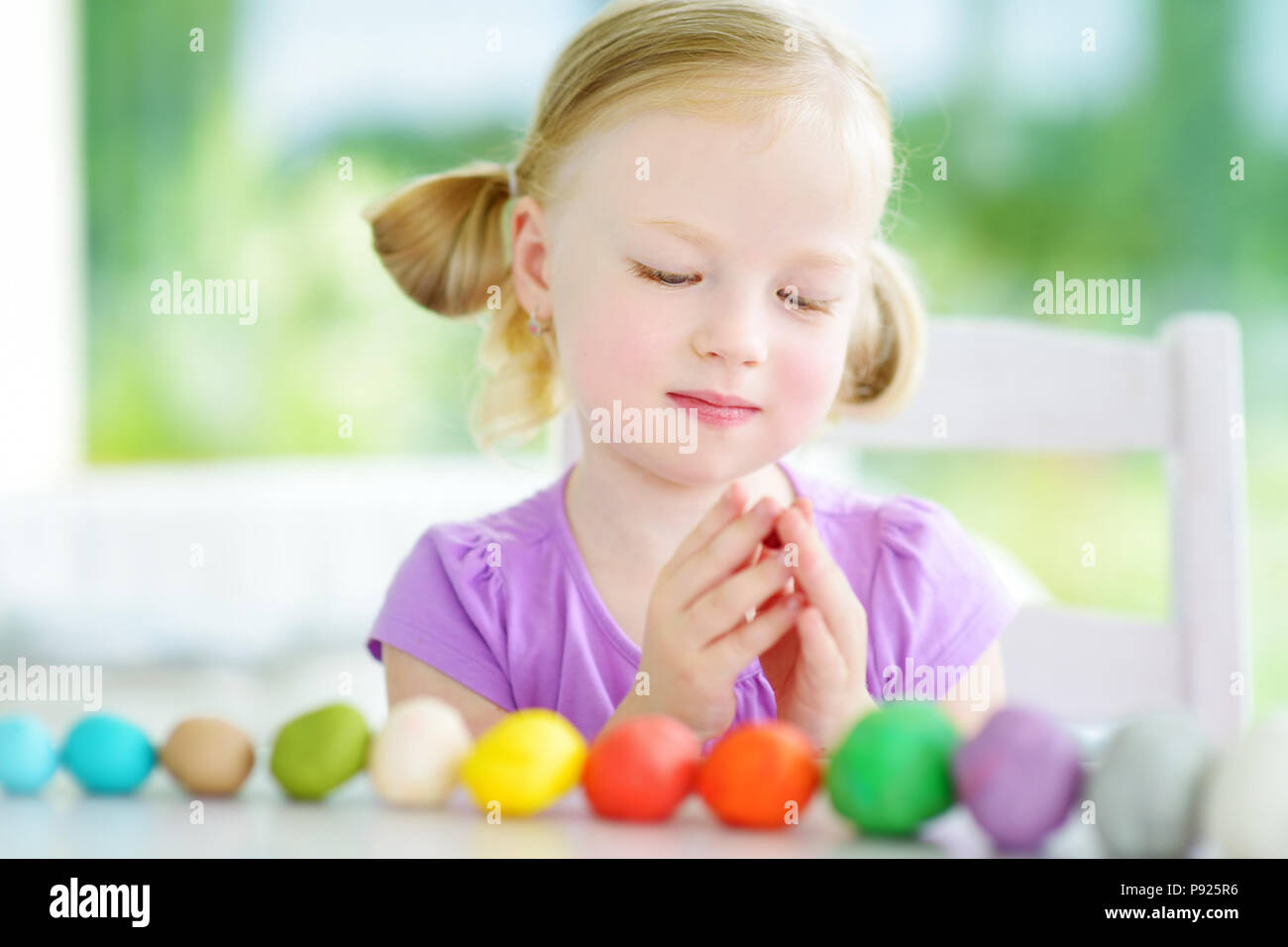Cute little girl having fun with colorful modeling clay at a daycare ...