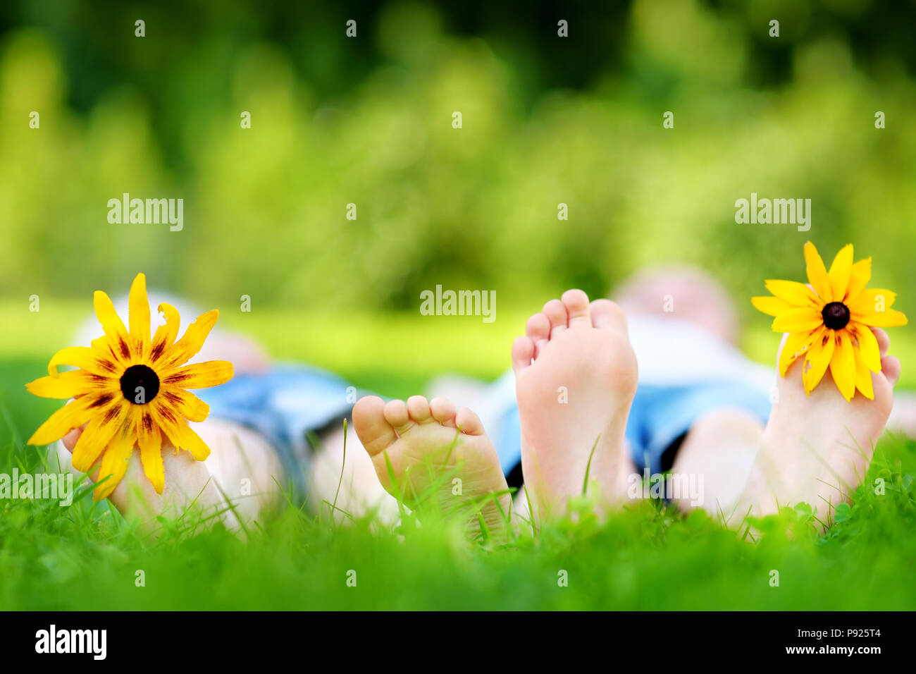 Two children feet decorated with yellow flowers on grass outdoors in ...