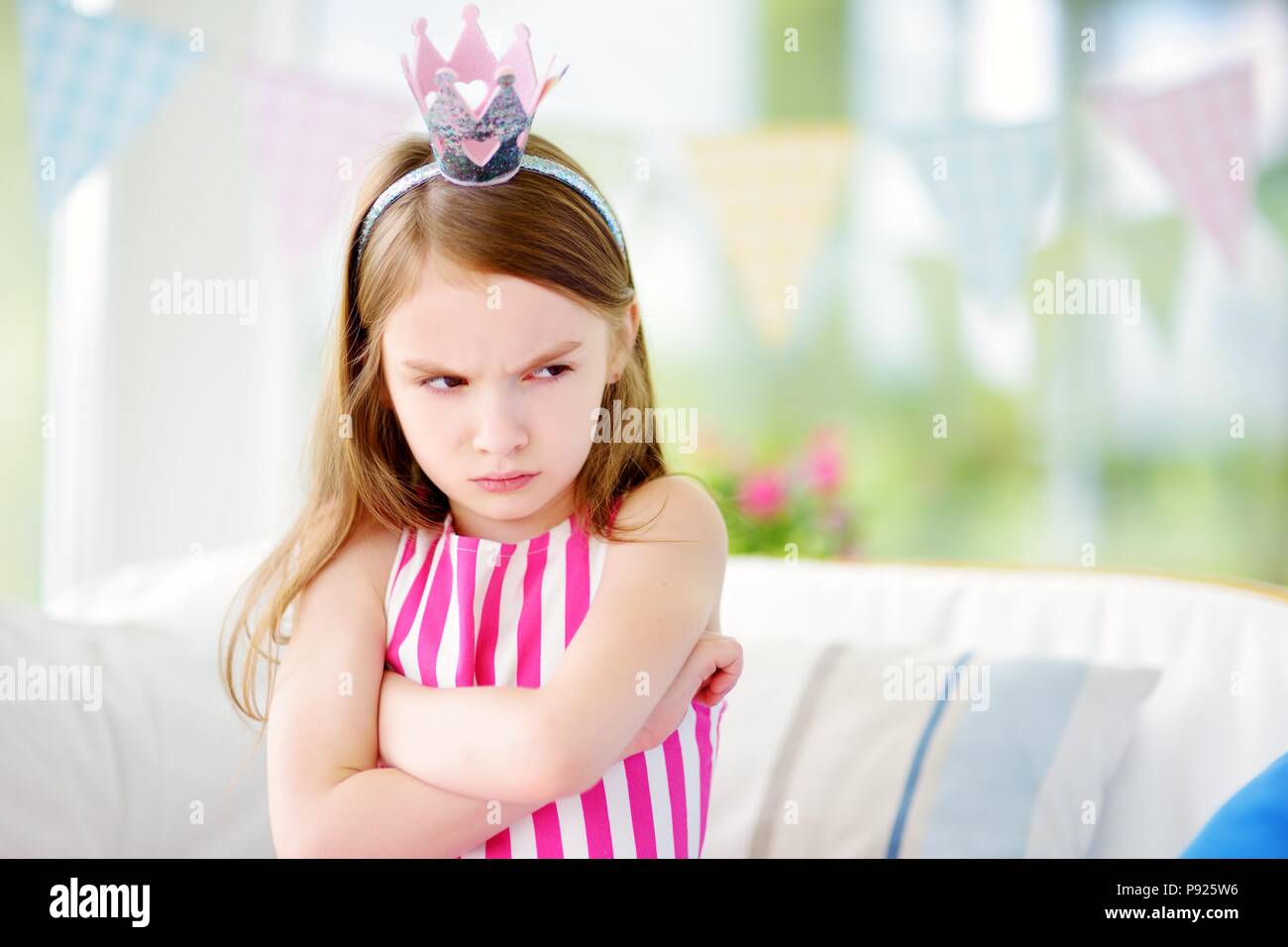 Moody little girl wearing princess tiara feeling angry and unsatisfied ...