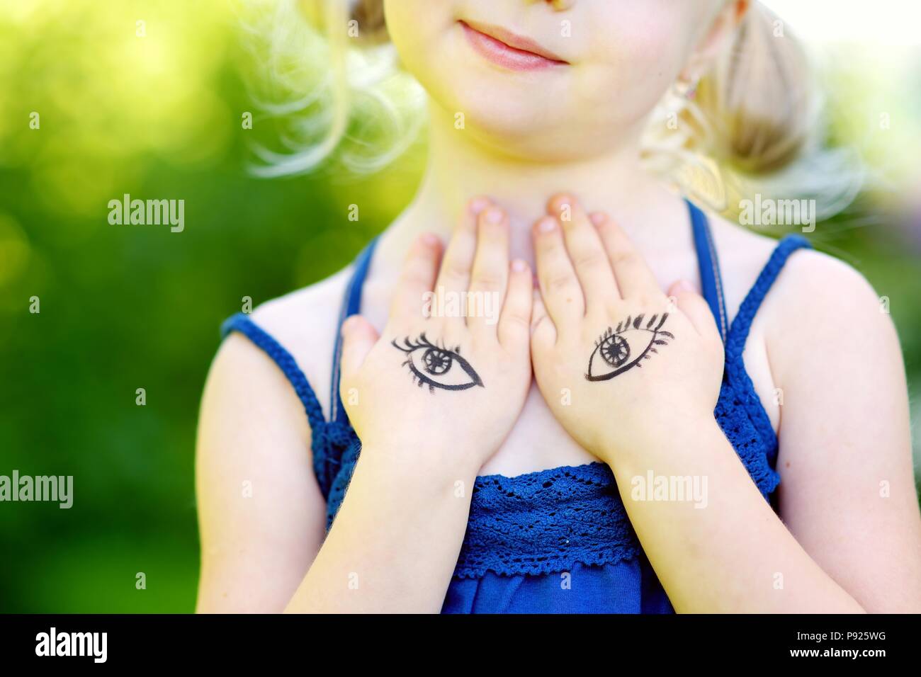 Cute little girl covering her chest with her hands on summer day ...