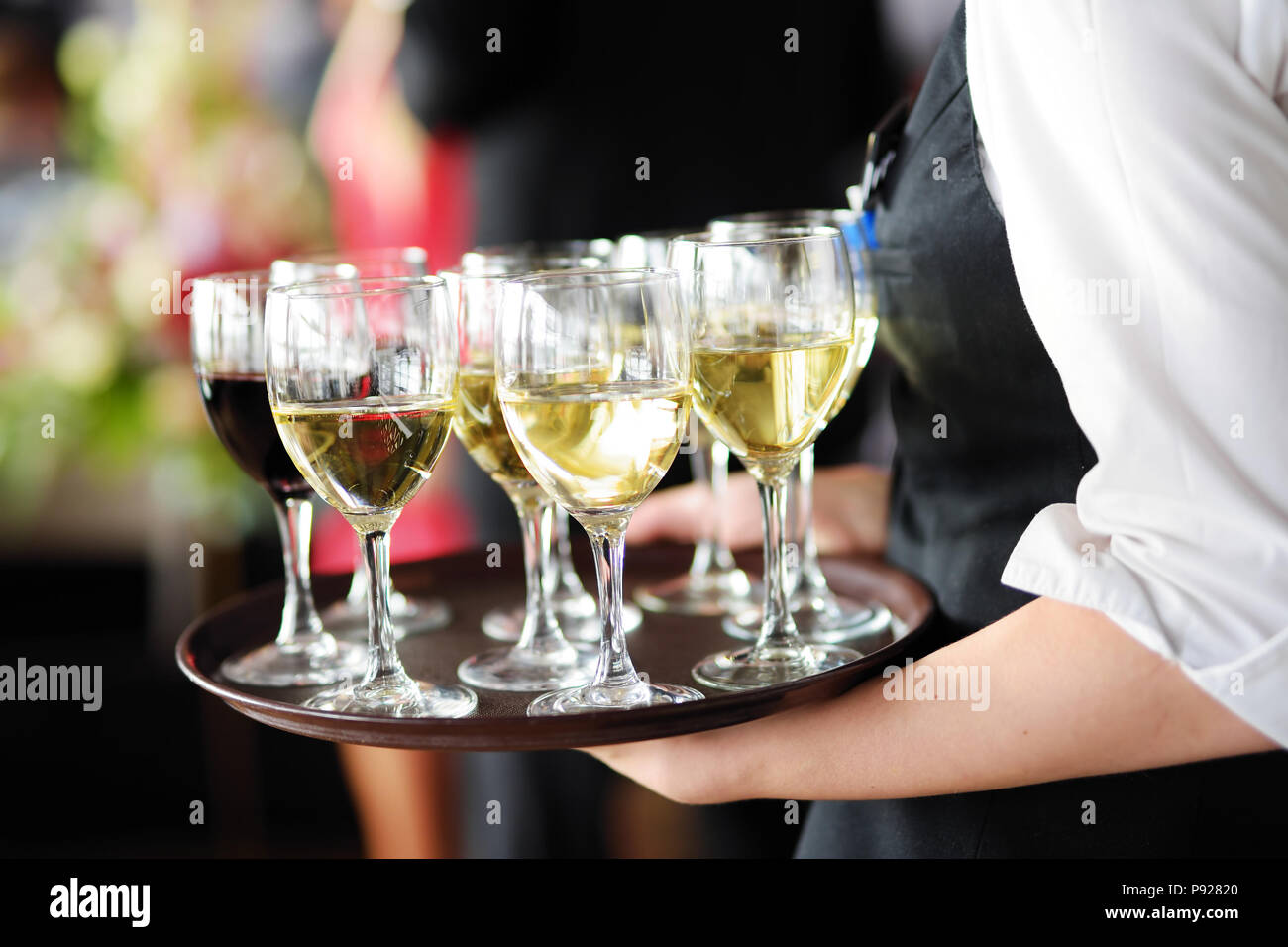 Waitress holding a dish of champagne and wine glasses at festive event ...