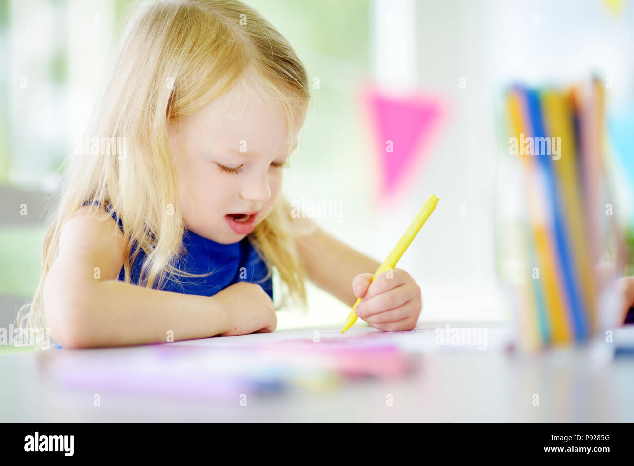 Cute little girl drawing with colorful pencils at a daycare. Creative ...
