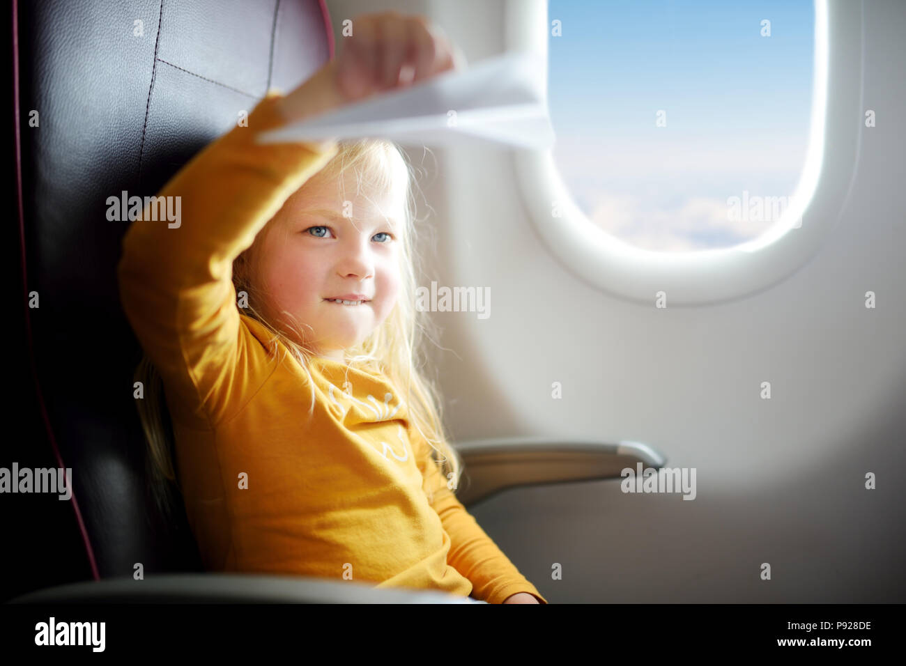 Adorable little girl traveling by an airplane. Child sitting by ...