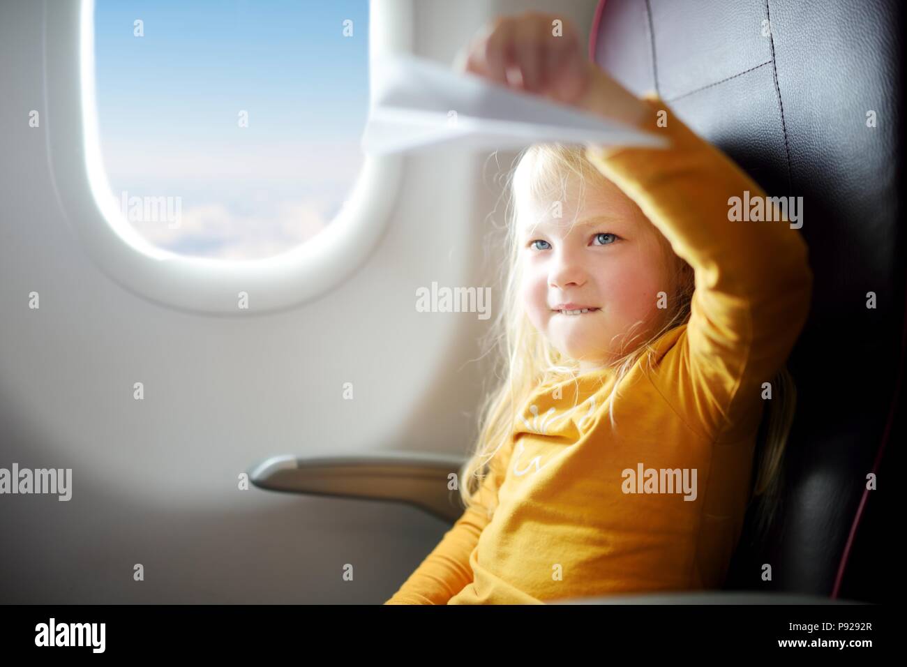 Adorable little girl traveling by an airplane. Child sitting by ...