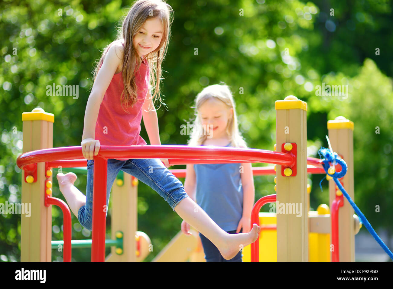 Two cute little girls having fun on a playground outdoors in summer ...