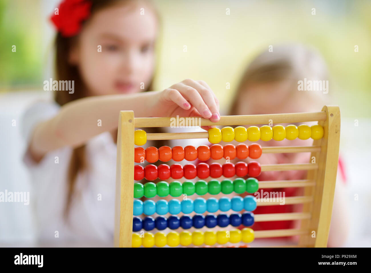 Two cute little girls playing with abacus at home. Big sister teaching ...