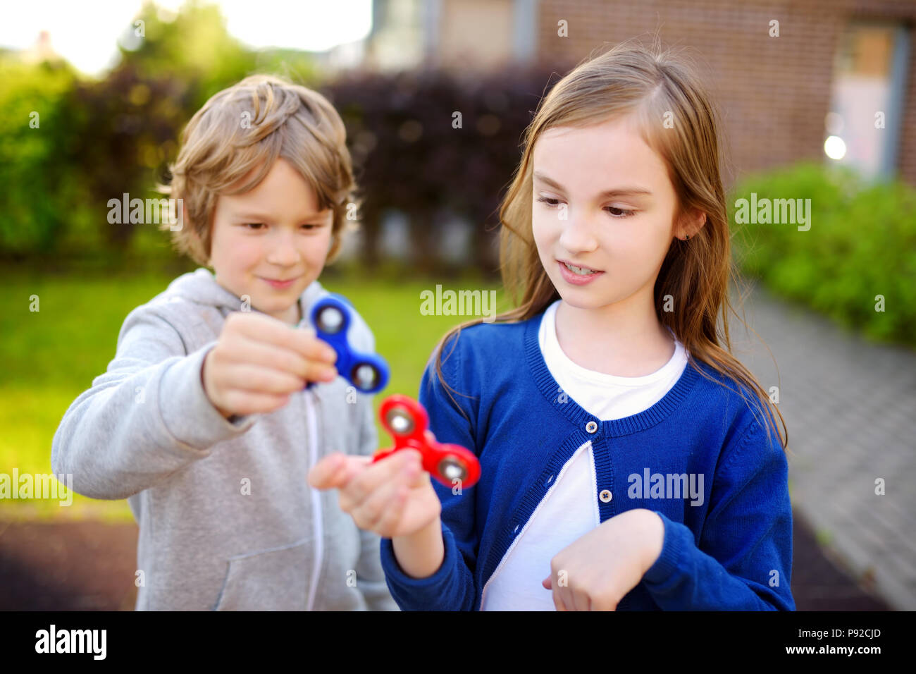 Two funny friends playing with colorful fidget spinners on the ...