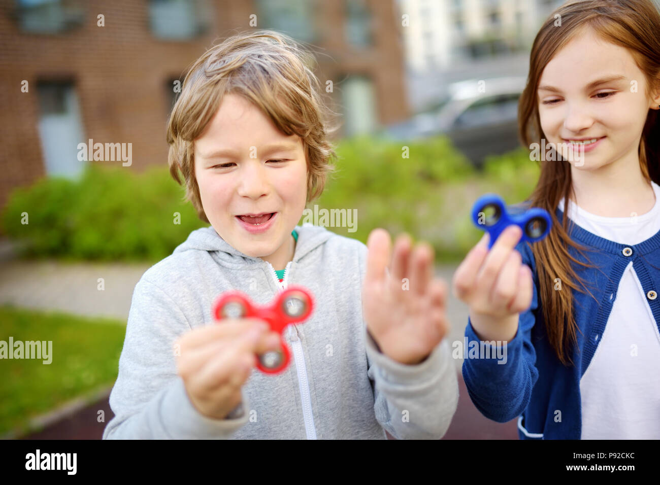 Two funny friends playing with colorful fidget spinners on the ...