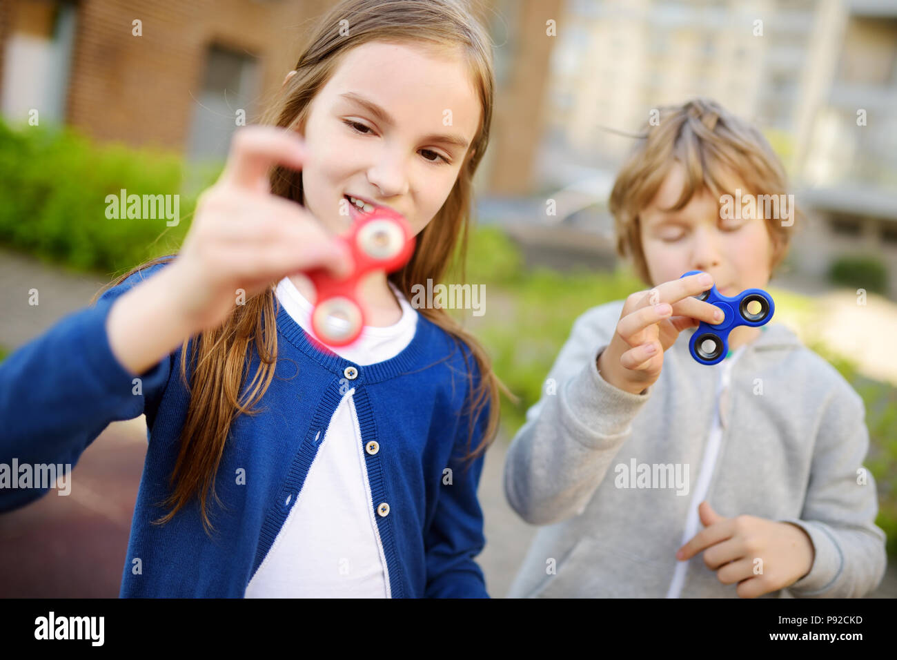 Two funny friends playing with colorful fidget spinners on the ...