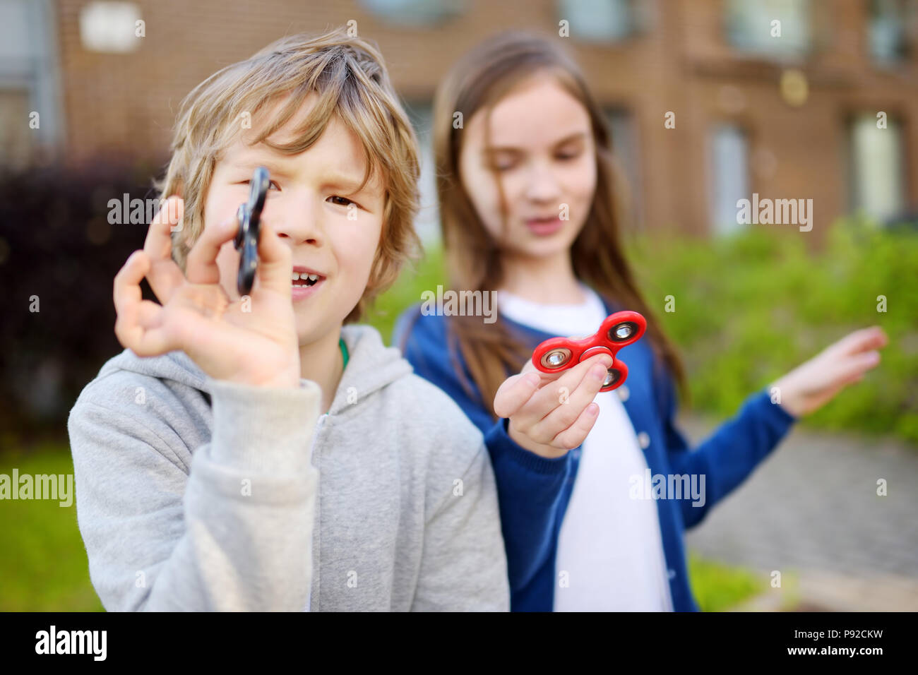 Two funny friends playing with colorful fidget spinners on the ...