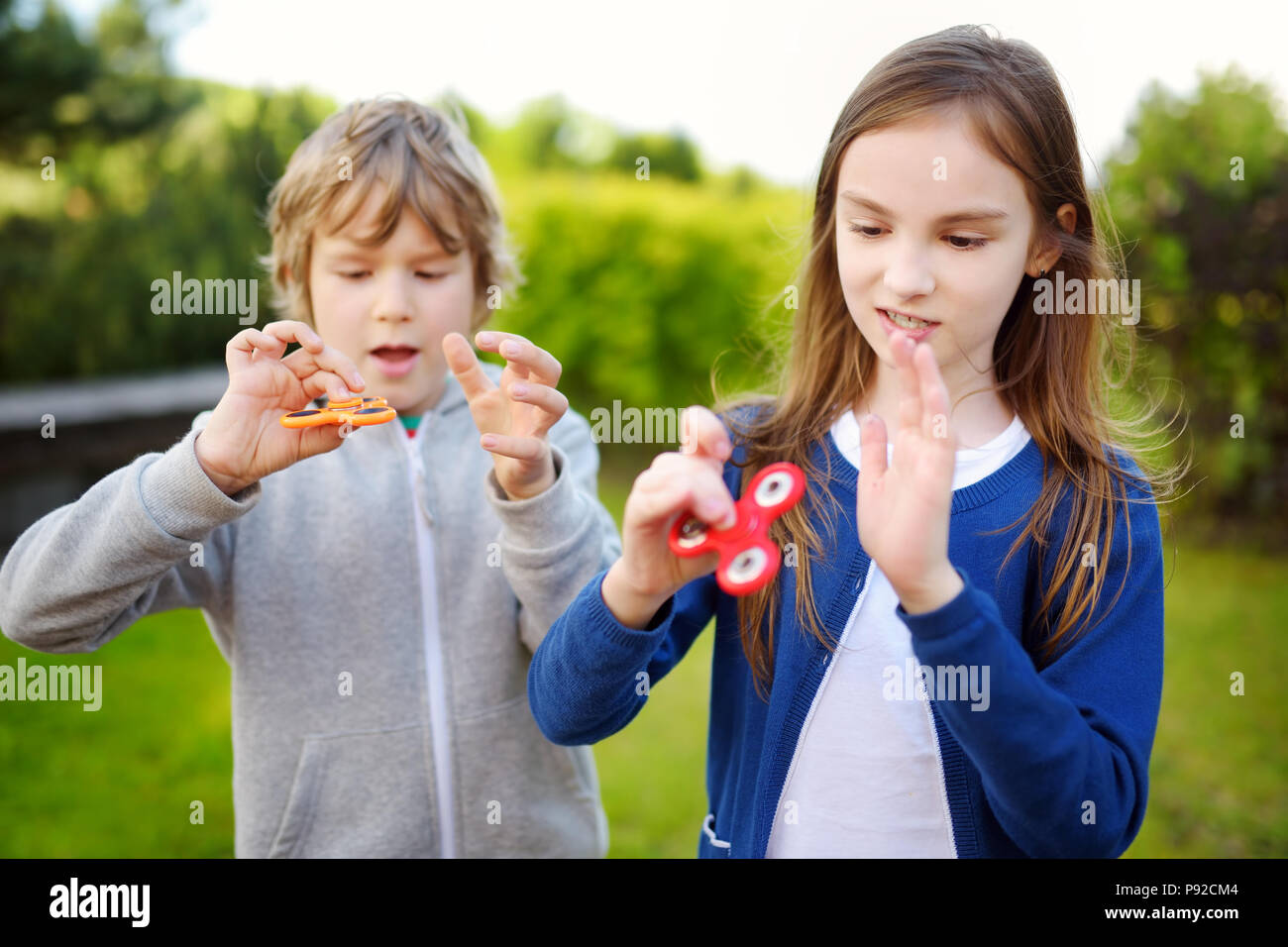 Two funny friends playing with colorful fidget spinners on the ...