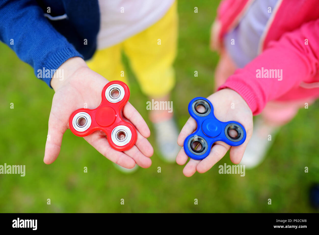 Two school children playing with colorful fidget spinners on the ...
