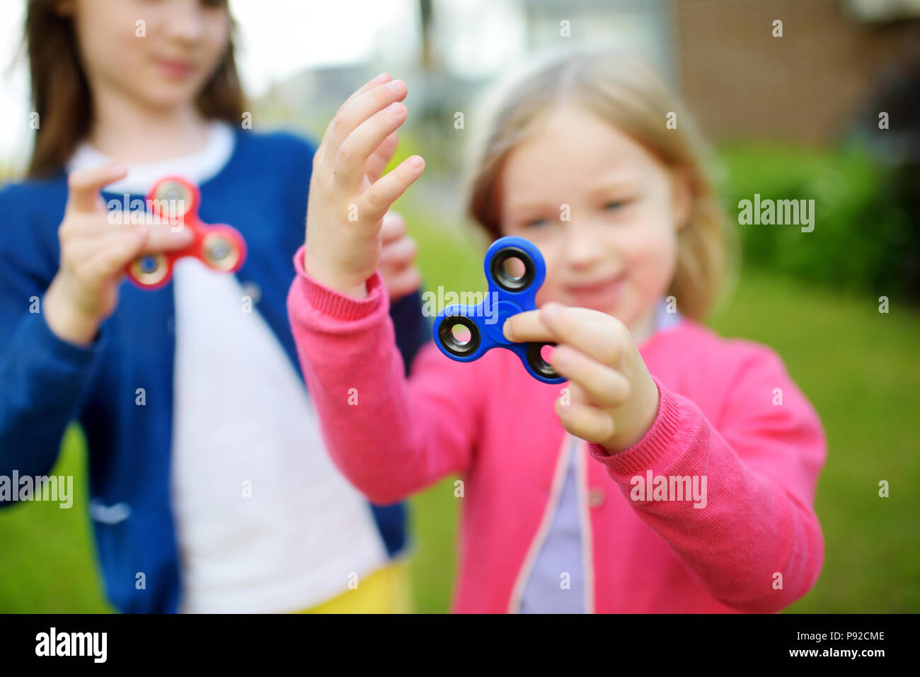 Two funny sisters playing with colorful fidget spinners on the ...