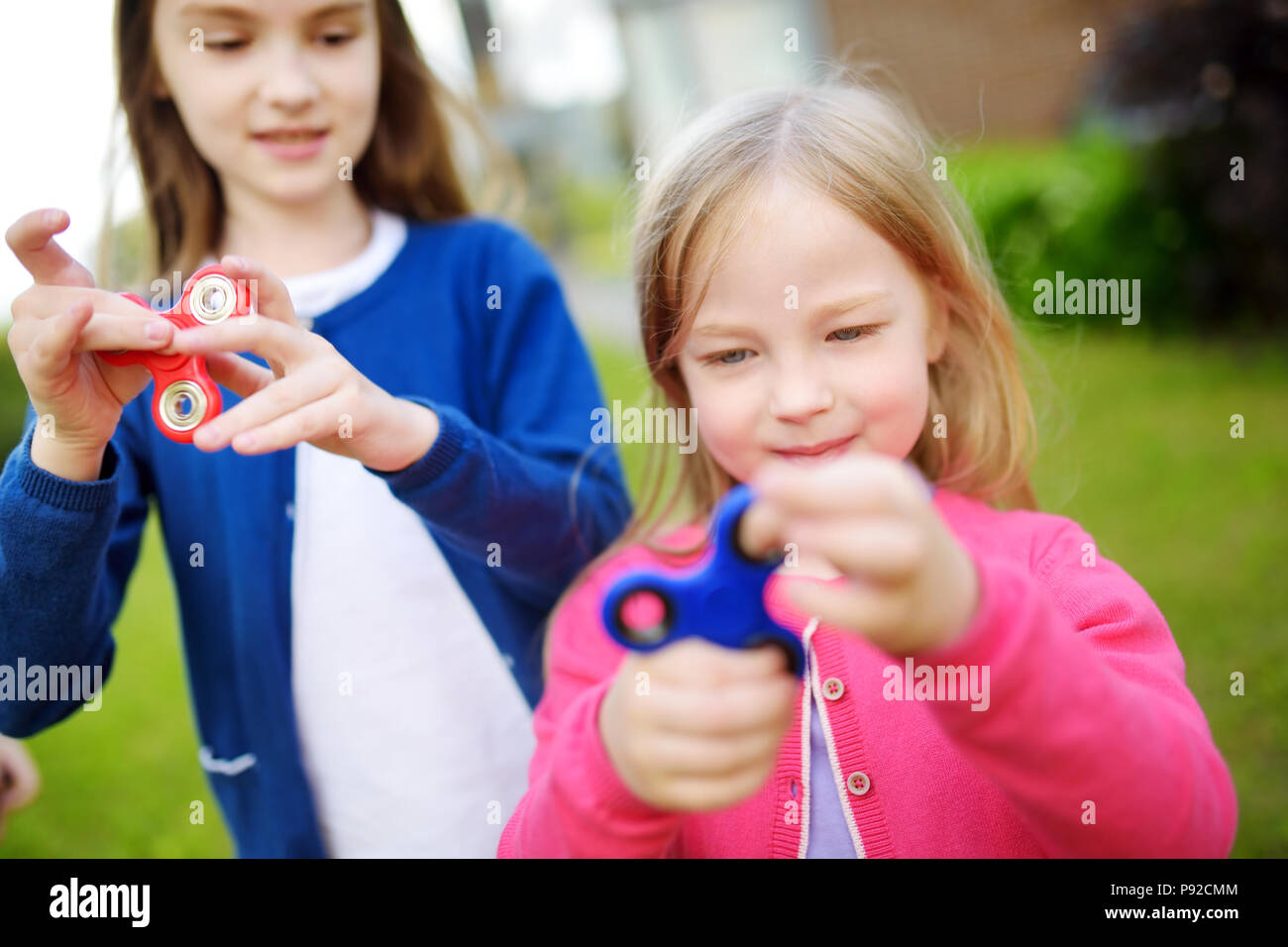 Two funny sisters playing with colorful fidget spinners on the ...