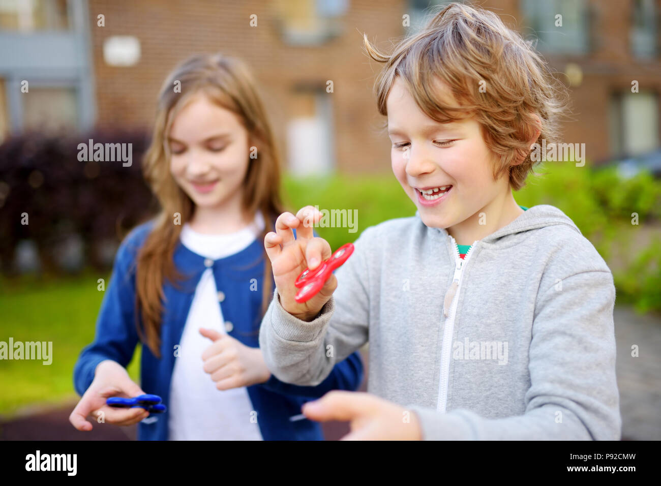 Two funny friends playing with colorful fidget spinners on the ...