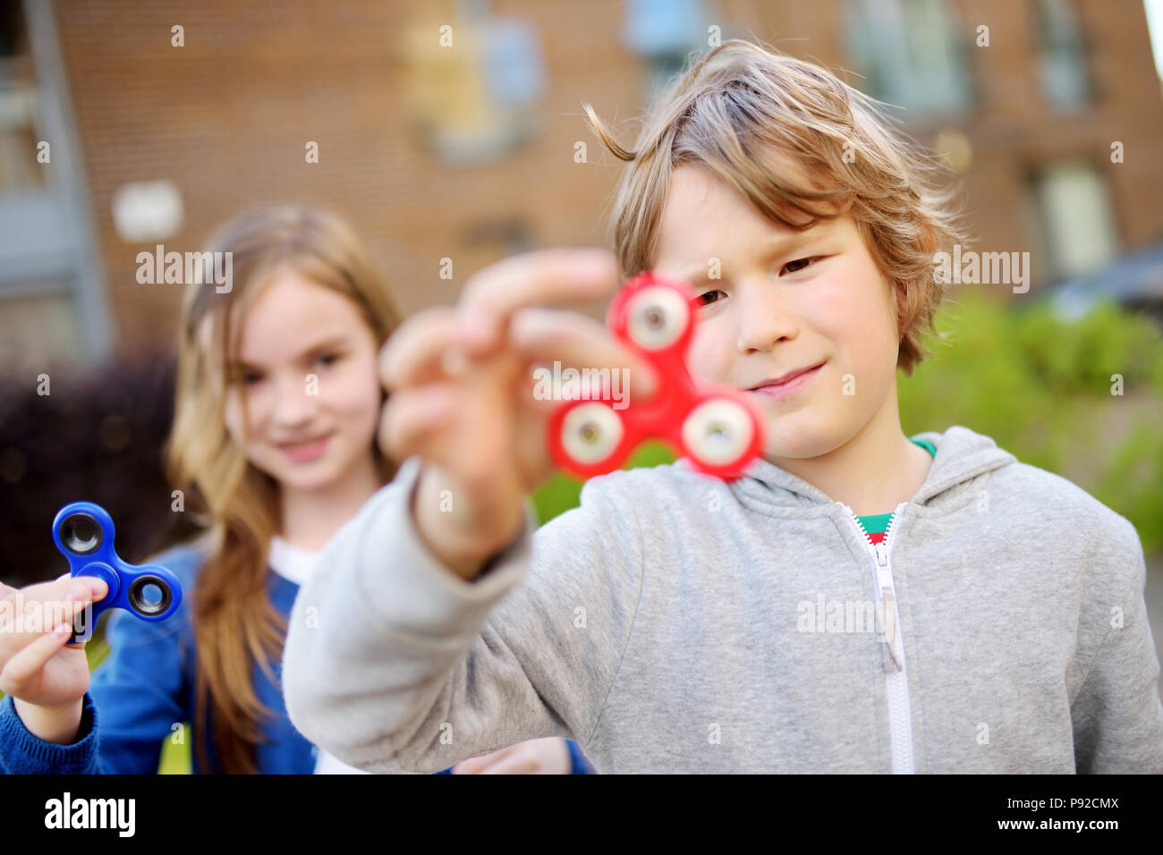 Two funny friends playing with colorful fidget spinners on the ...