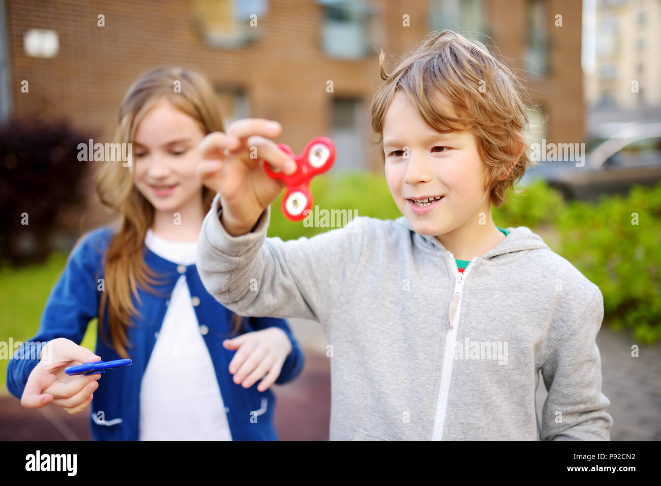 Two funny friends playing with colorful fidget spinners on the ...