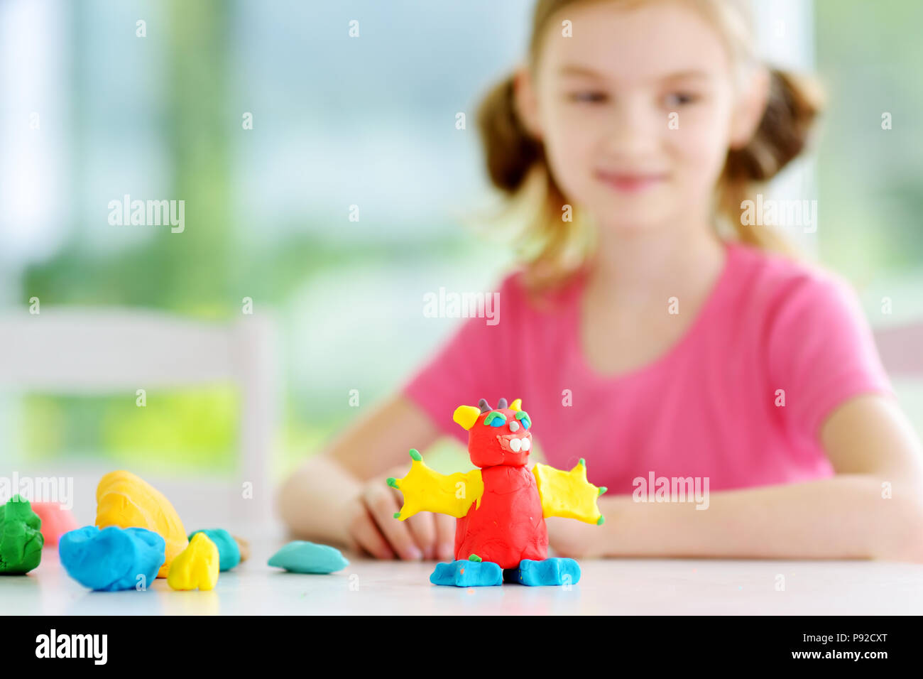 Cute little girl having fun with colorful modeling clay at a daycare ...