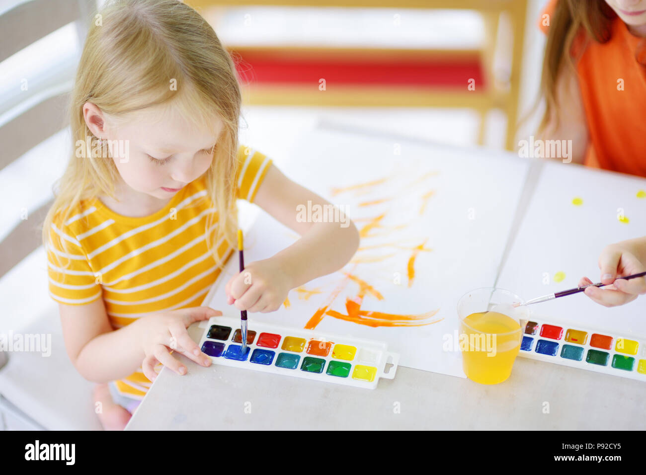Cute little girl drawing with colorful paints at a daycare. Creative ...