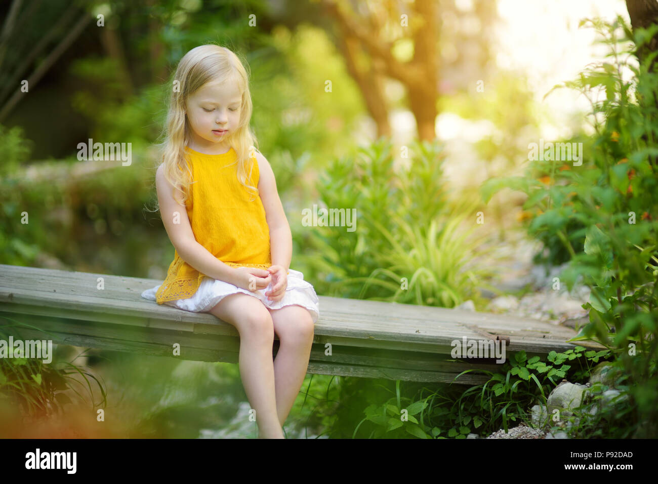 Adorable little girl having fun on warm and sunny summer day in a park ...