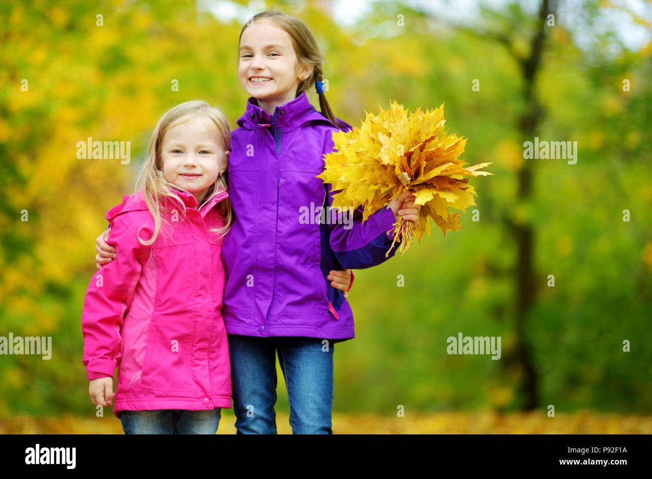Two cute little girls having fun on beautiful autumn day. Happy ...