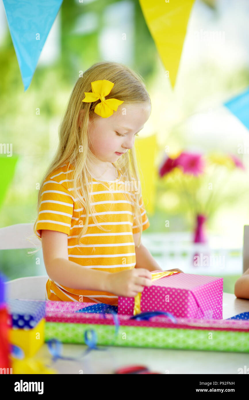 Cute preschooler girl wrapping gifts in colorful wrapping paper ...