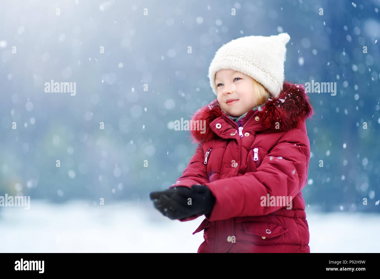 Adorable little girl having fun in beautiful winter park. Cute child ...
