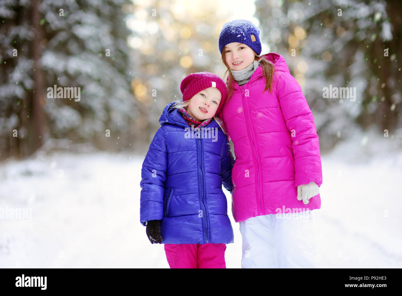 Two adorable little girls having fun together in beautiful winter park ...