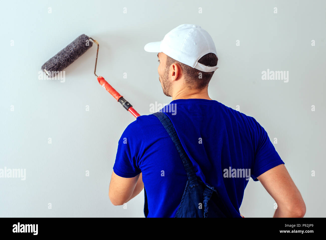 Young painter worker in overall during painting job Stock Photo - Alamy