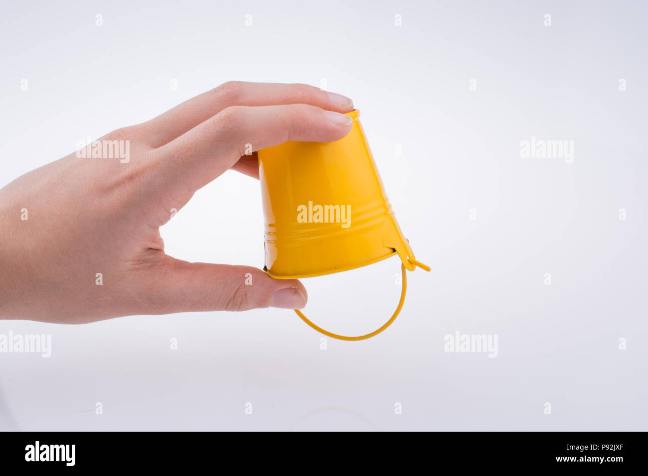 Hand holding a yellow bucket on a white background Stock Photo - Alamy