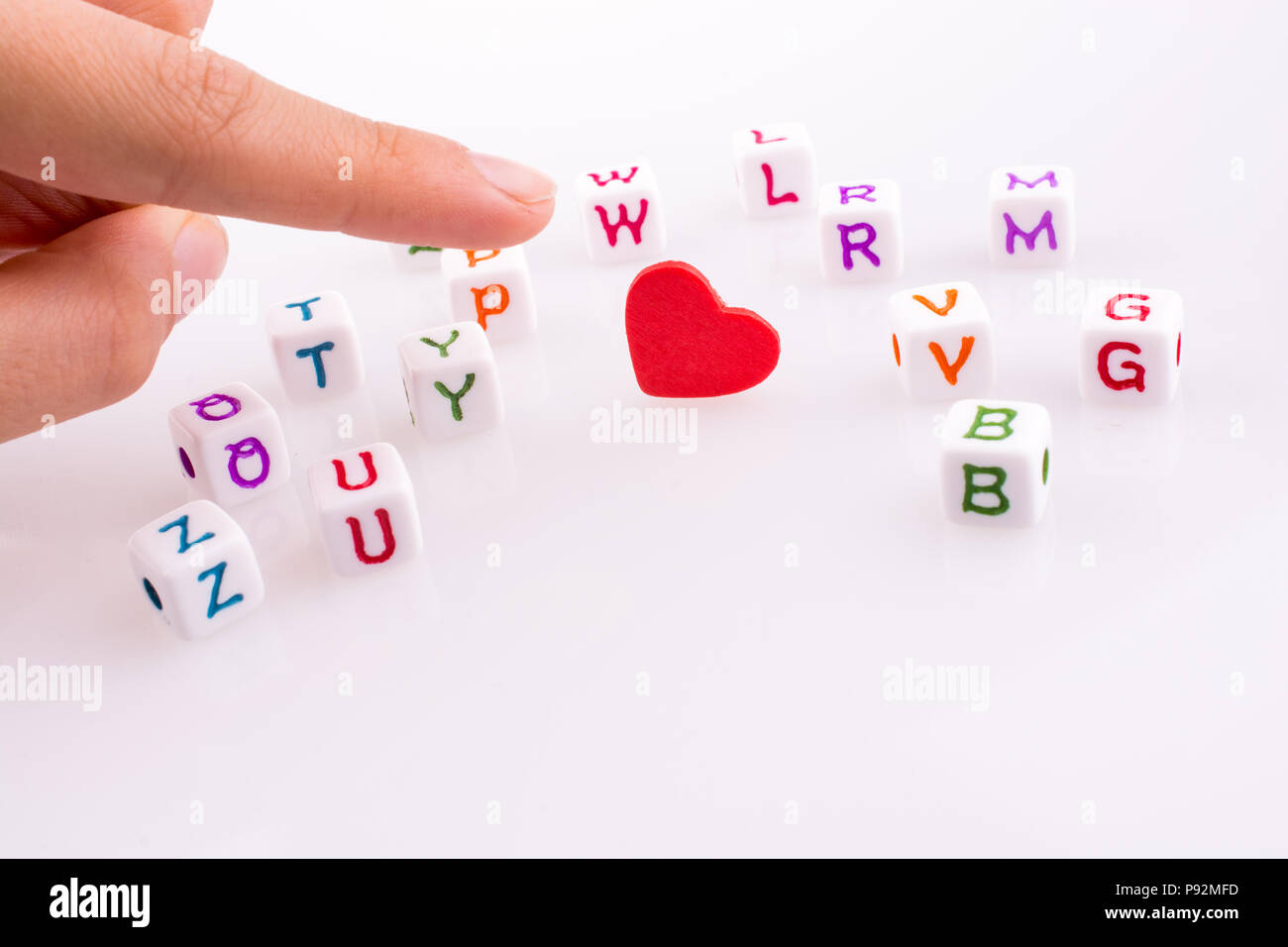 Hand pointing at Heart between Letter cubes on a white background Stock ...