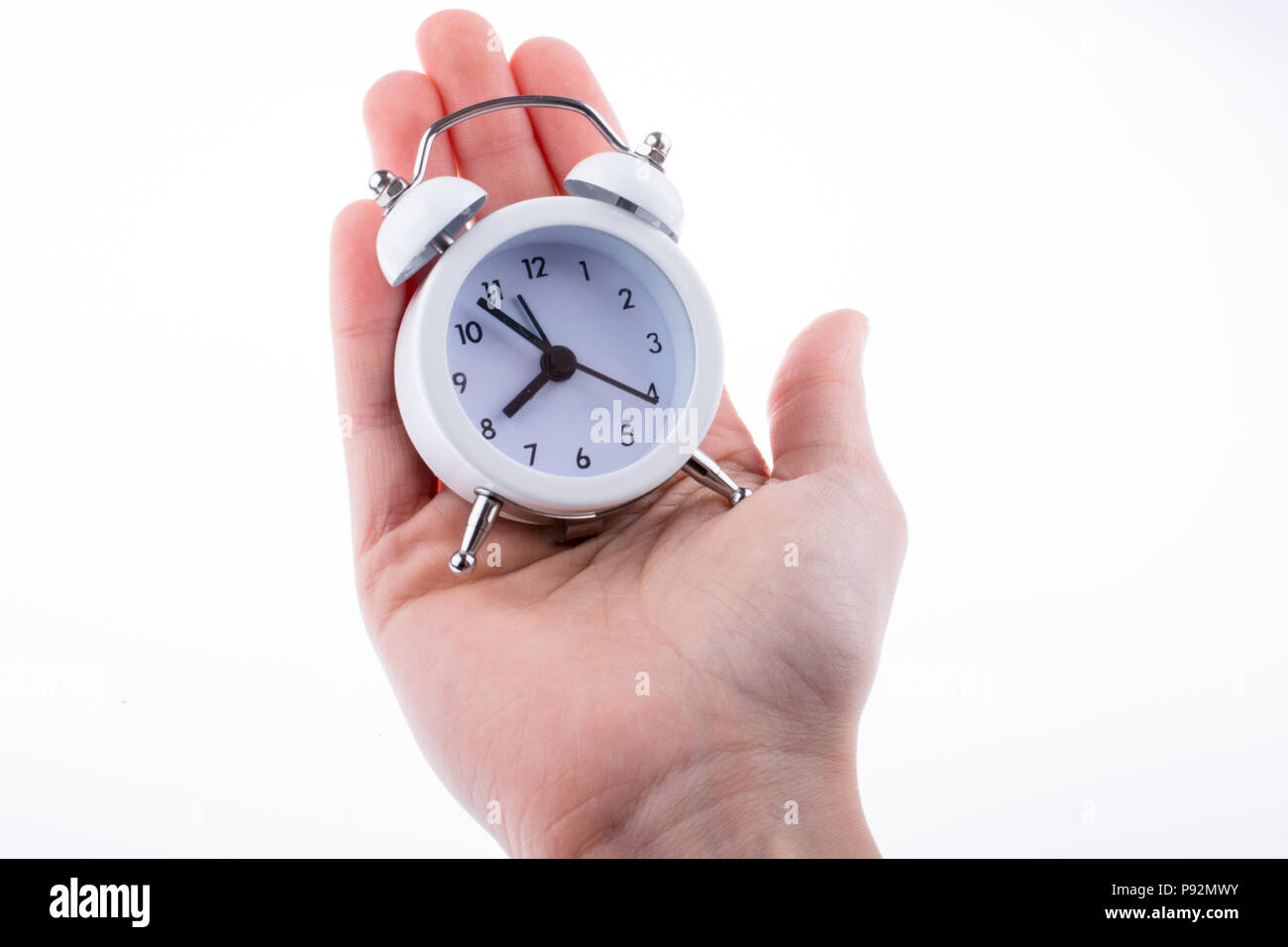 Alarm clock in hand on a white background Stock Photo - Alamy