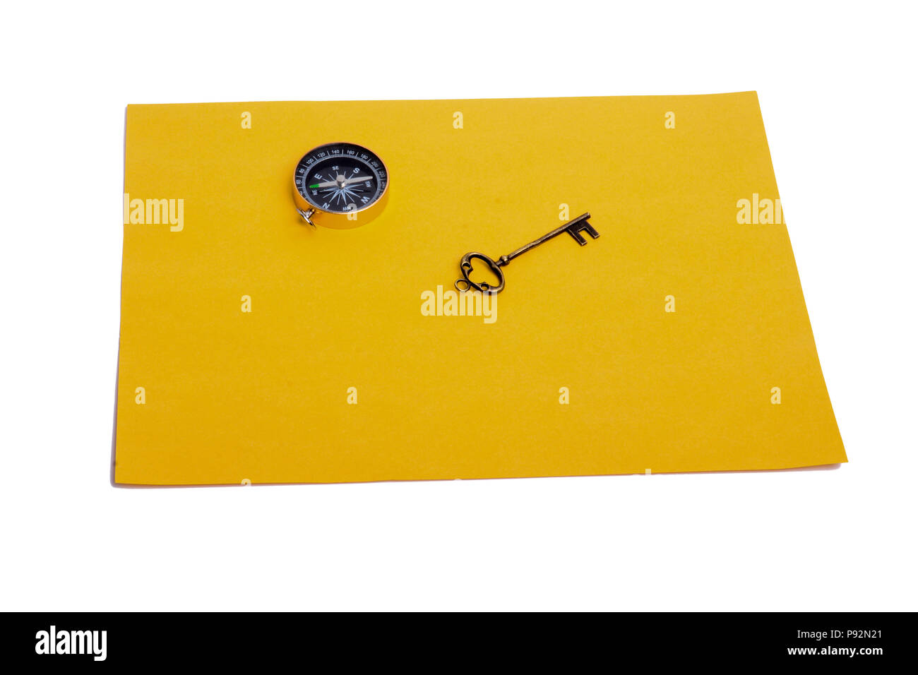 key and compass on a sheet of colored plain paper with a white ...
