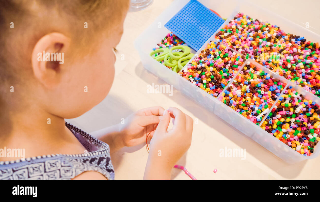 Little girl making bracelet from colorful kids beads Stock Photo - Alamy