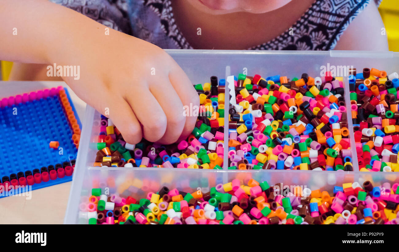 Little girl making bracelet from colorful kids beads Stock Photo - Alamy