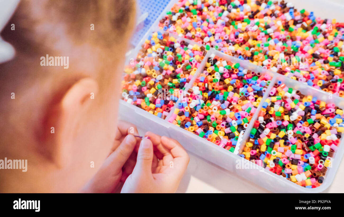 Little girl making bracelet from colorful kids beads Stock Photo - Alamy