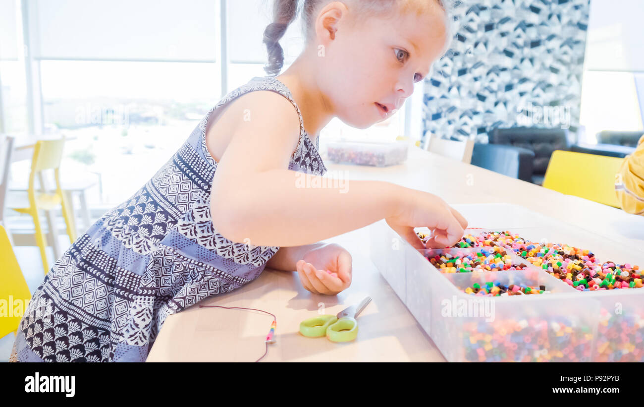 Little girl making bracelet from colorful kids beads Stock Photo - Alamy
