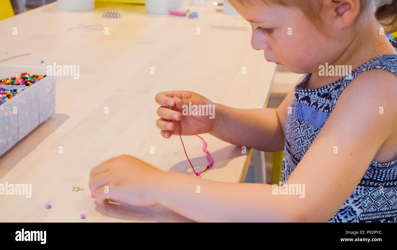 Little girl making bracelet from colorful kids beads Stock Photo - Alamy