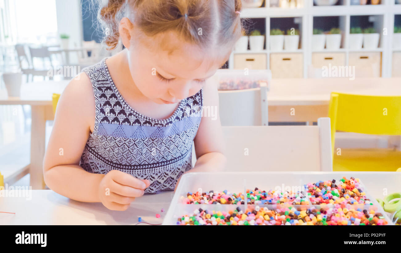 Little girl making bracelet from colorful kids beads Stock Photo - Alamy