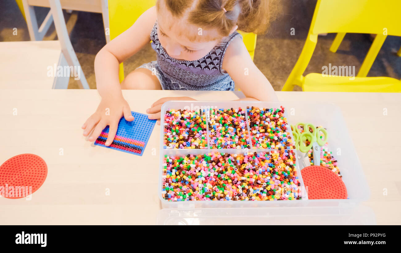 Little girl making bracelet from colorful kids beads Stock Photo - Alamy