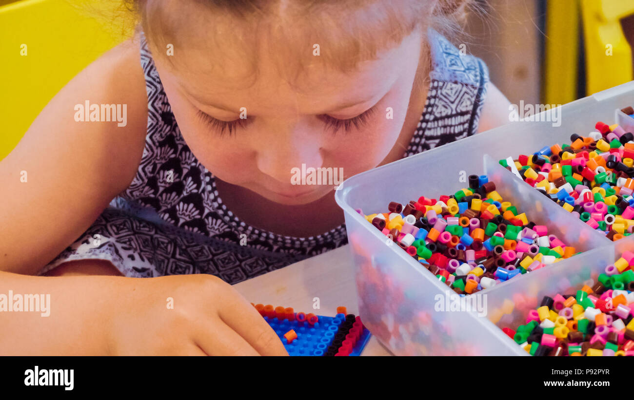 Little girl making bracelet from colorful kids beads Stock Photo - Alamy