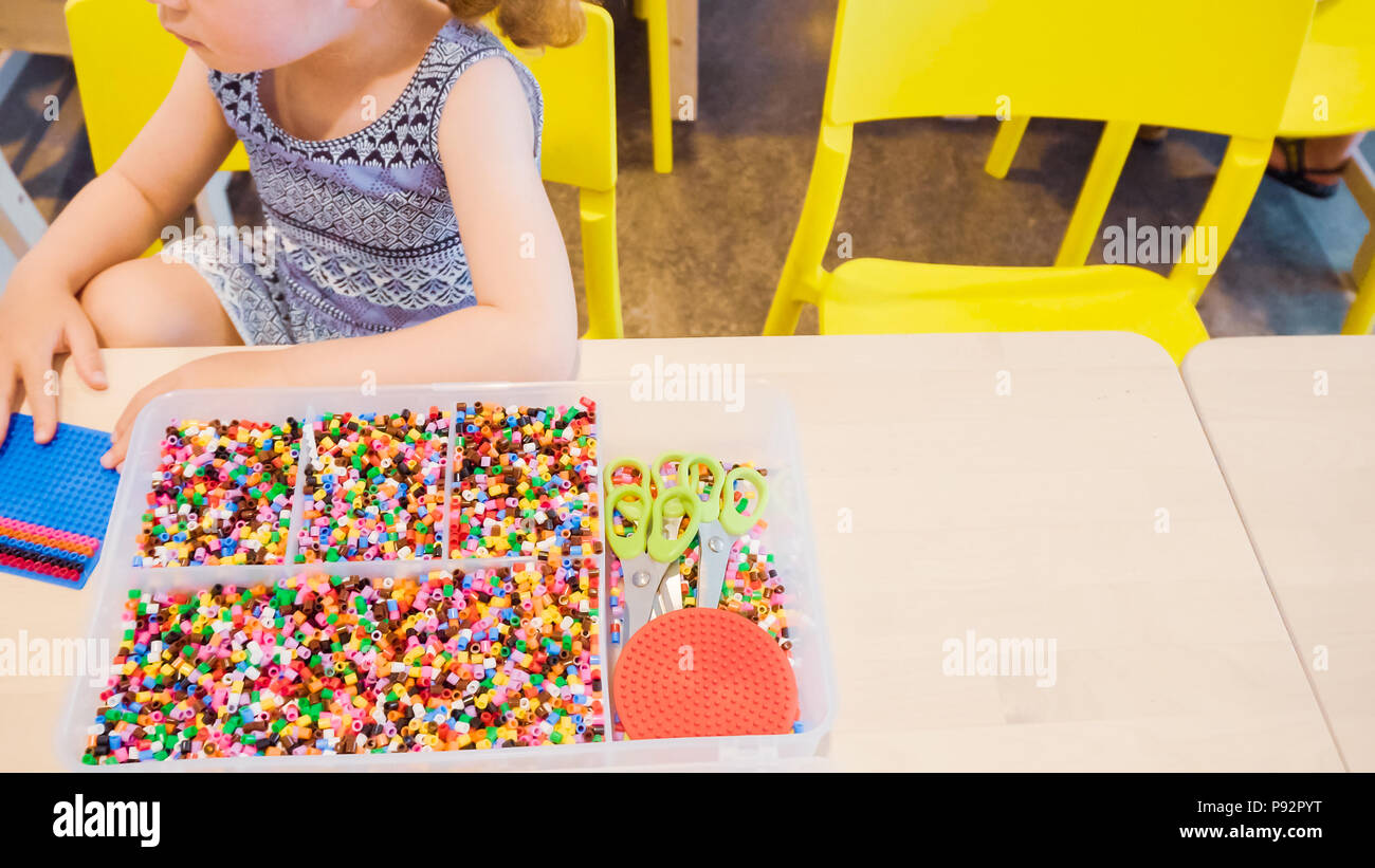 Little girl making bracelet from colorful kids beads Stock Photo - Alamy