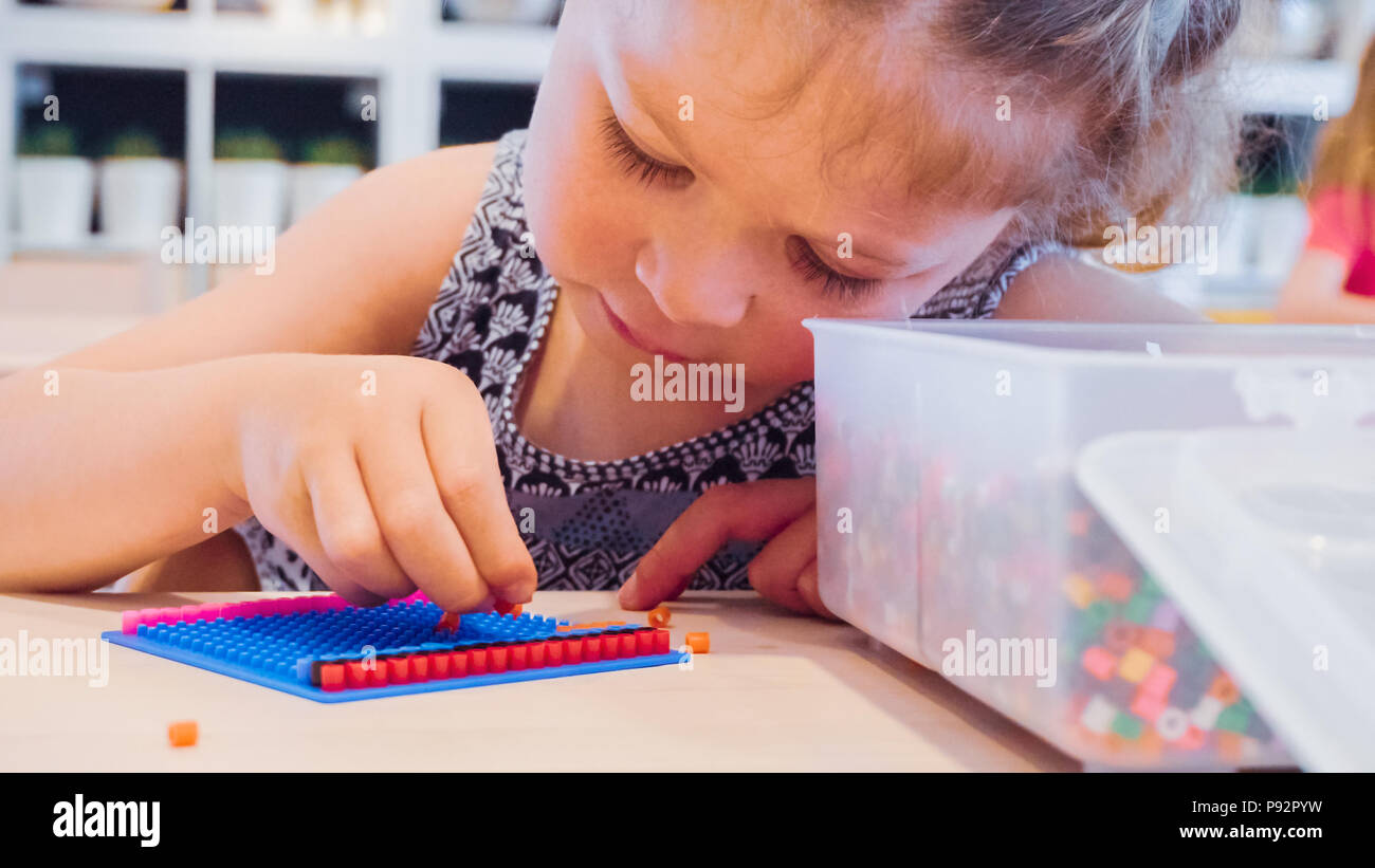 Little girl making bracelet from colorful kids beads Stock Photo - Alamy