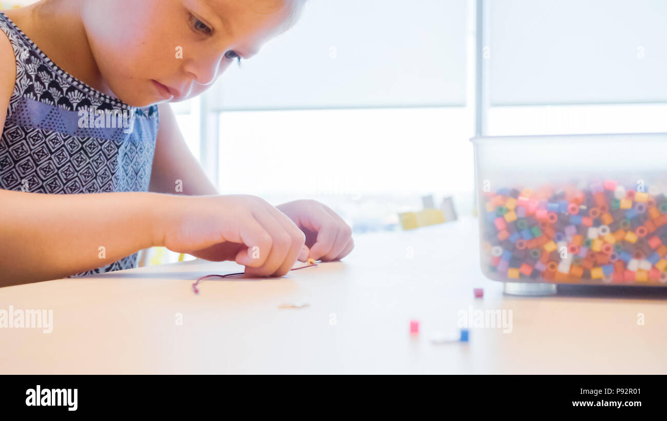 Little girl making bracelet from colorful kids beads Stock Photo - Alamy