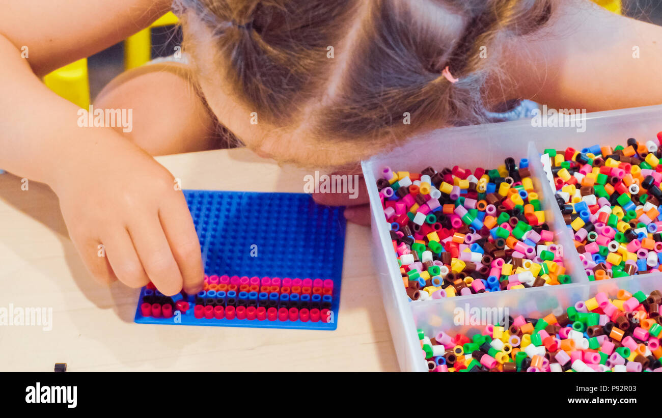 Little girl making bracelet from colorful kids beads Stock Photo - Alamy