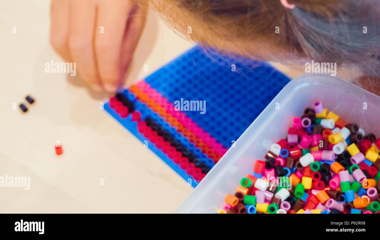 Little girl making bracelet from colorful kids beads Stock Photo - Alamy
