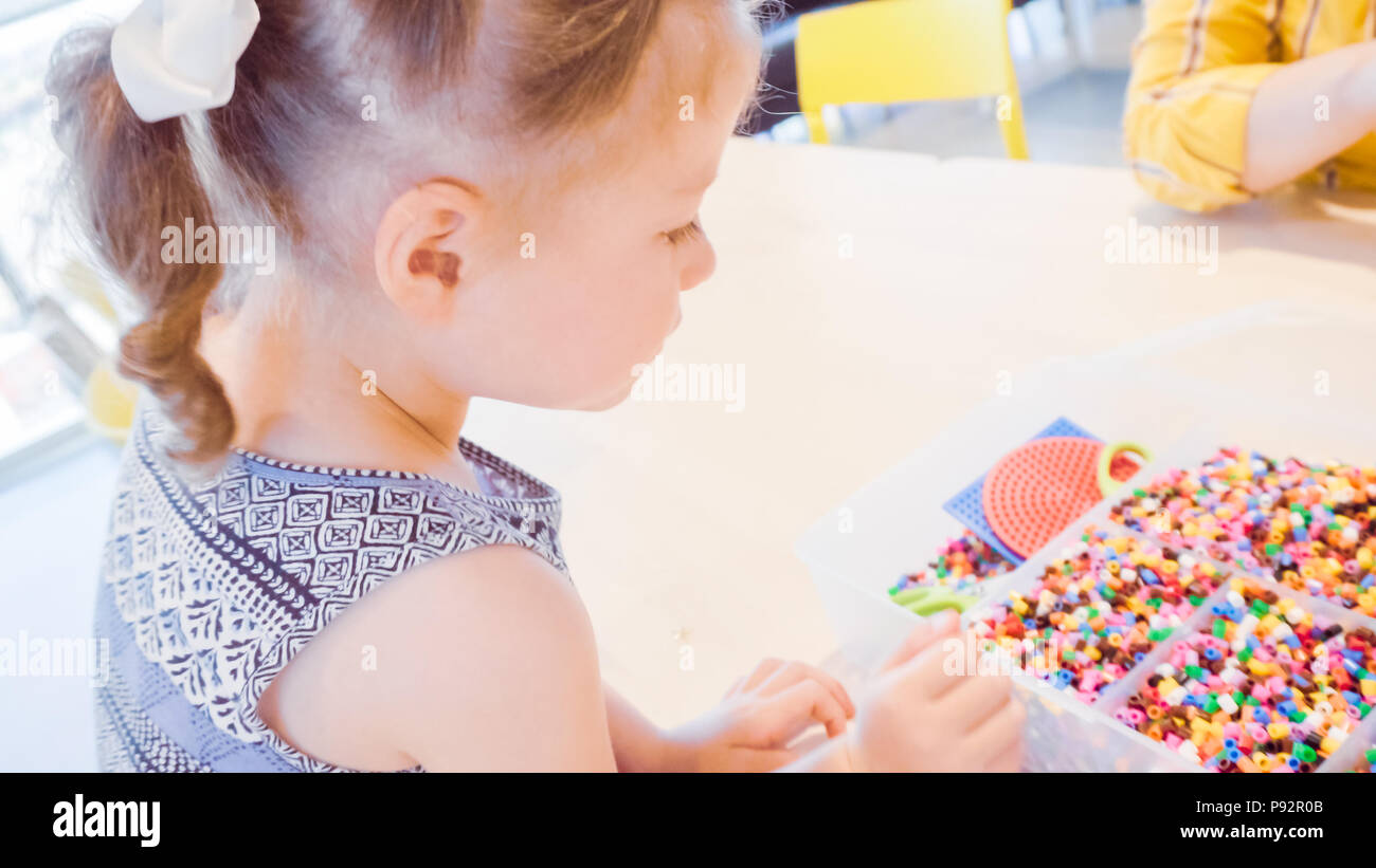 Little girl making bracelet from colorful kids beads Stock Photo - Alamy