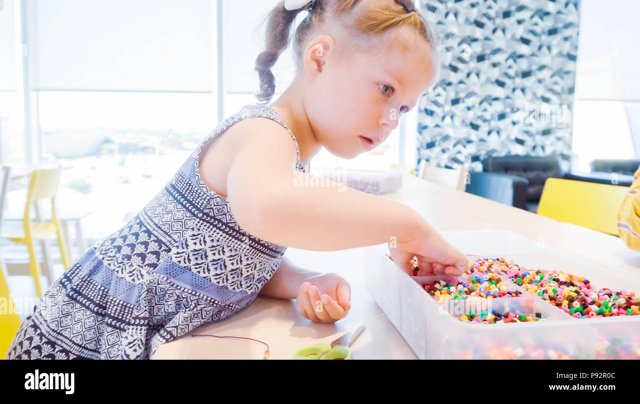 Little girl making bracelet from colorful kids beads Stock Photo - Alamy